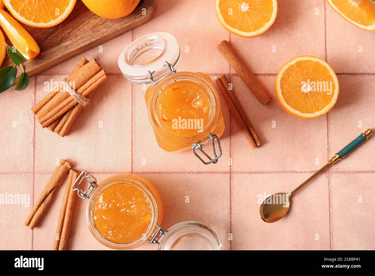 Jars of sweet orange jam with cinnamon and fruits on beige tile ...