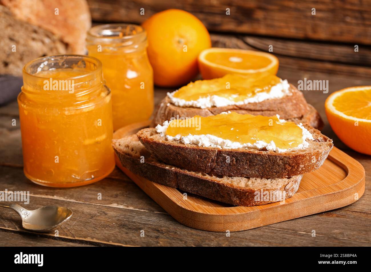 Jars of sweet orange jam and slices of bread on wooden background Stock ...