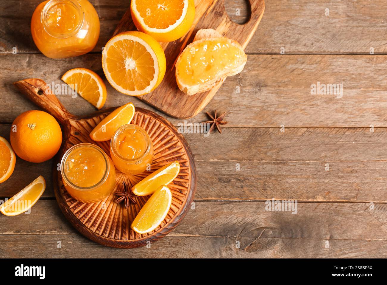 Jars of sweet orange jam with star anise and slices of bread on wooden ...