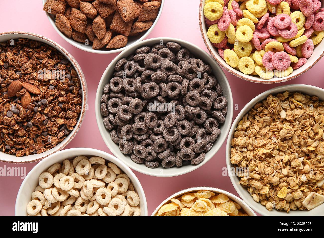 Bowls with different cornflakes on pink background Stock Photo - Alamy
