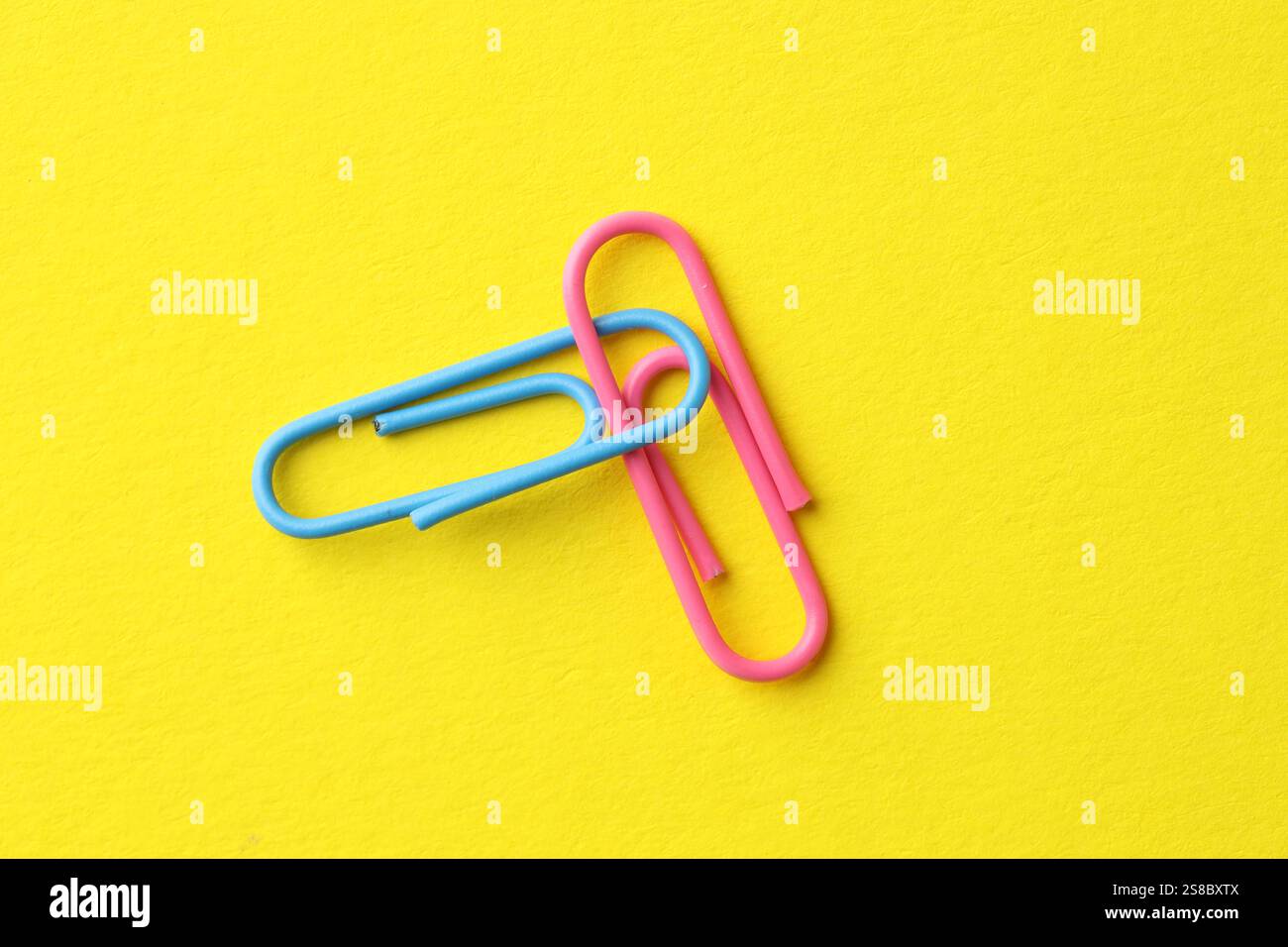 Two paper clips on yellow background, top view Stock Photo - Alamy