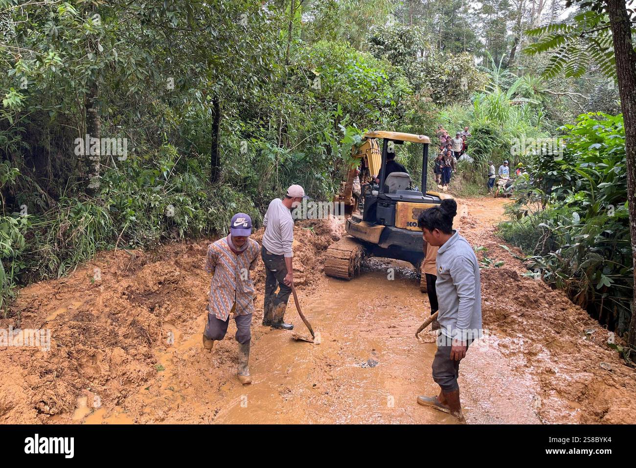 Workers clear a road cut off by a landslide following a flash flood in ...
