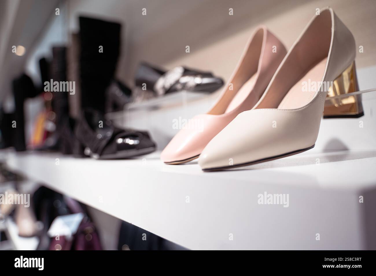 Chic pink and cream heels with gold accents displayed on a shelf in a ...