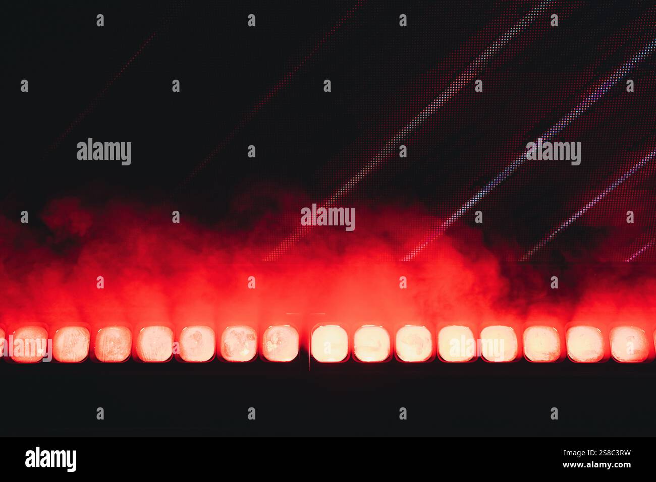 A vibrant display of bright red stage lights with a smoky atmospheric ...