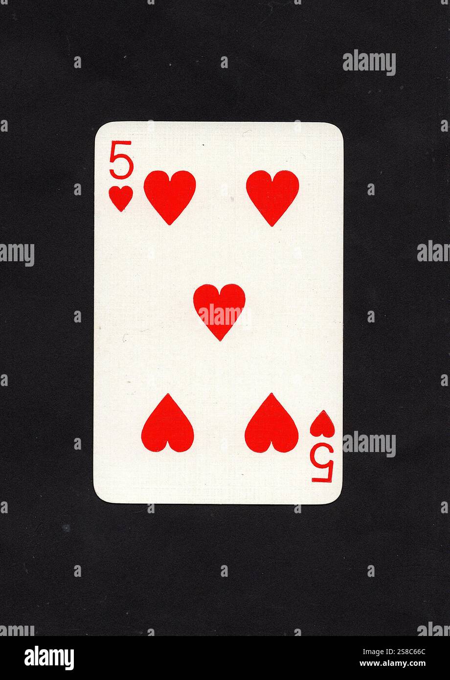A vintage five of hearts playing card isolated on a black background ...