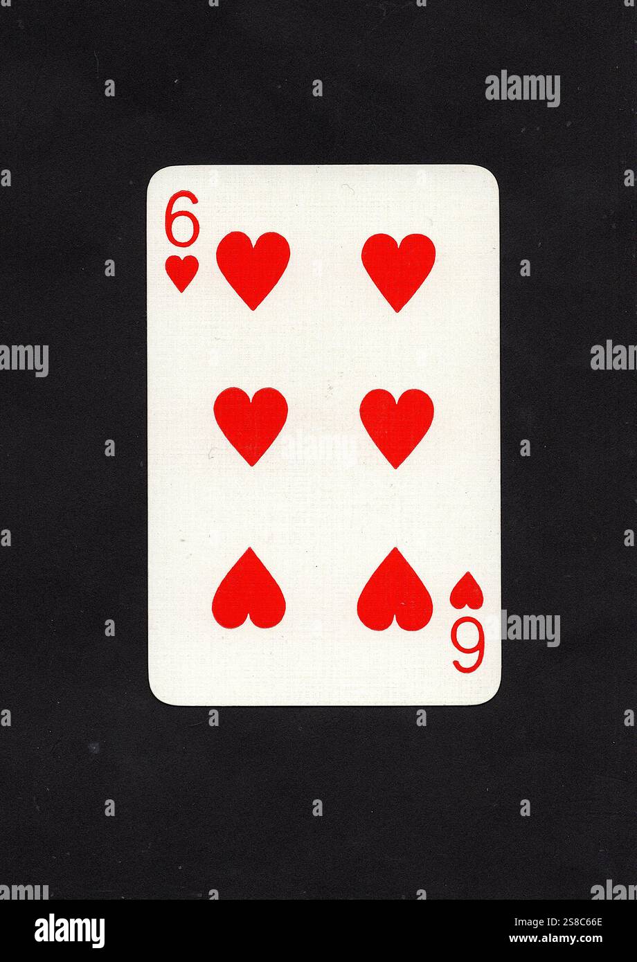 A vintage six of hearts playing card isolated on a black background ...