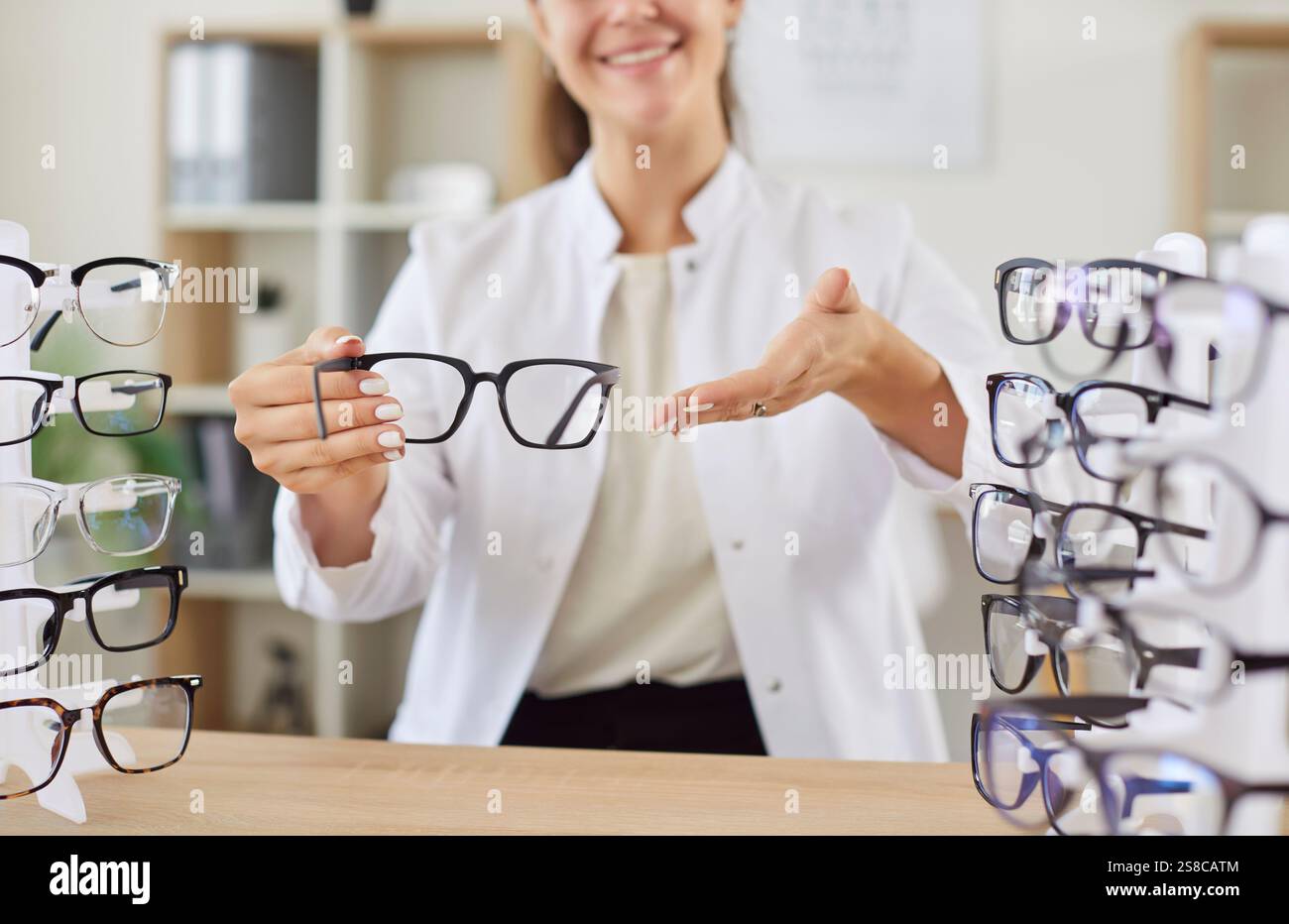 Smiling optician or ophthalmologist showing new glasses to improve ...