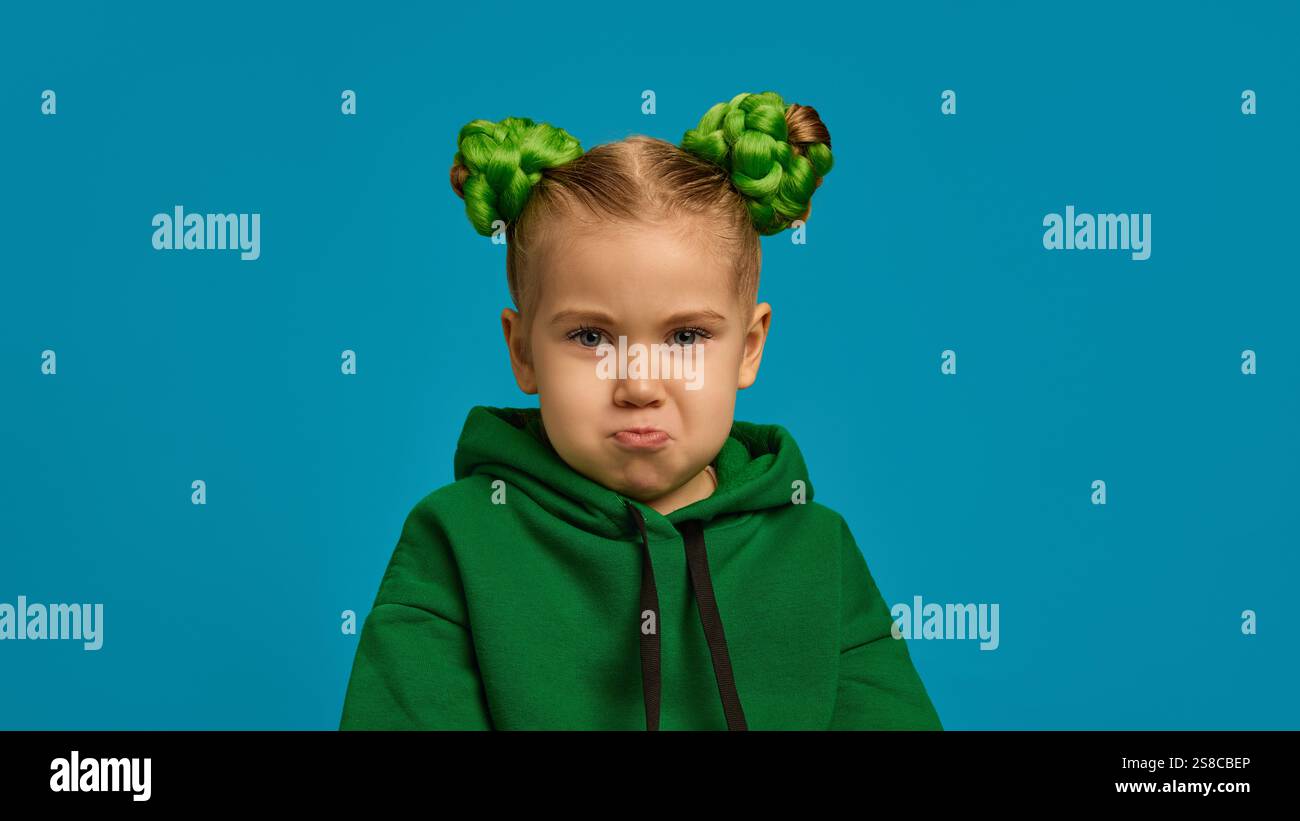 Preschool girl with pouty expression, in green hoodie, braided buns ...