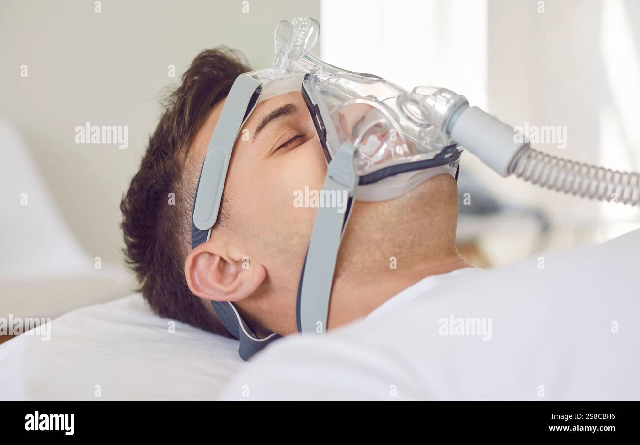 Patient wearing medical face oxygen mask with eyes closed, breathing ...