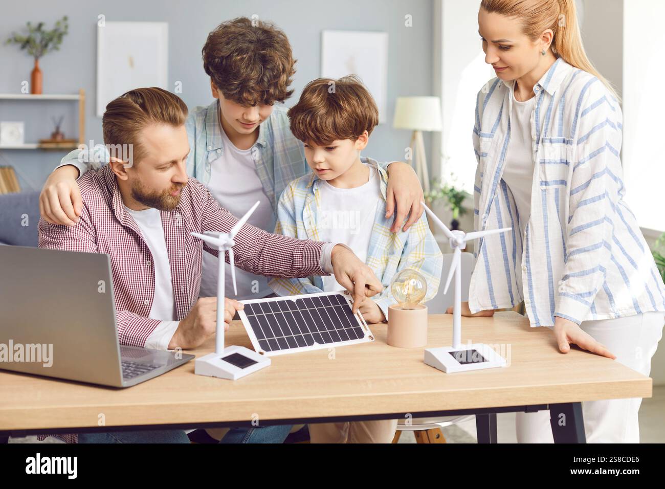 Young family with children looking to solar panel model and wind ...