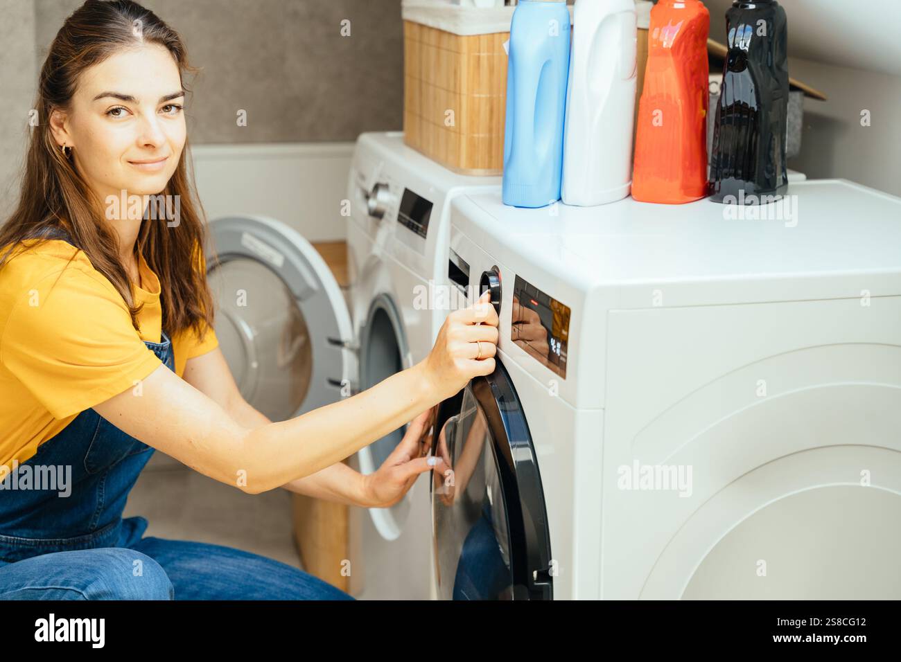 Beautiful young woman housewife doing housework, using washing machine ...