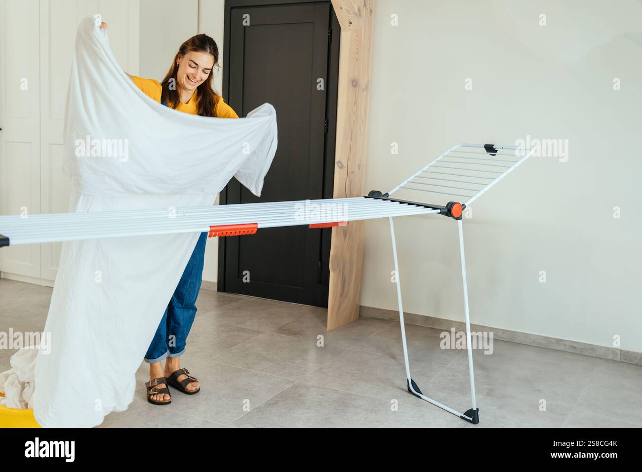 Full body height shot of house wife hangs clean laundry on a drying ...