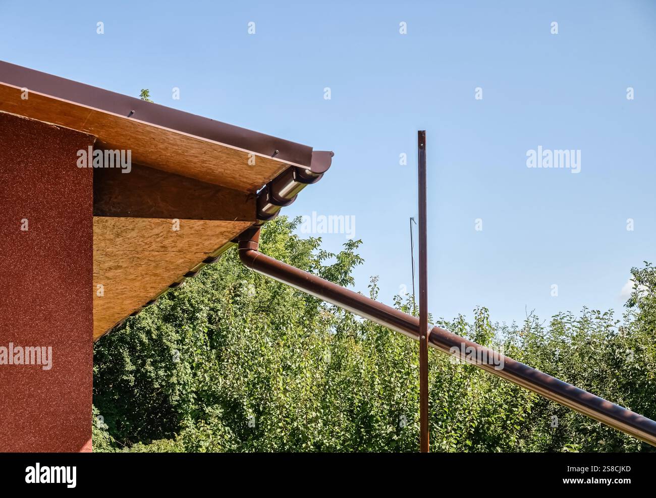 Close-up of a contemporary house roof corner with a brown gutter system ...
