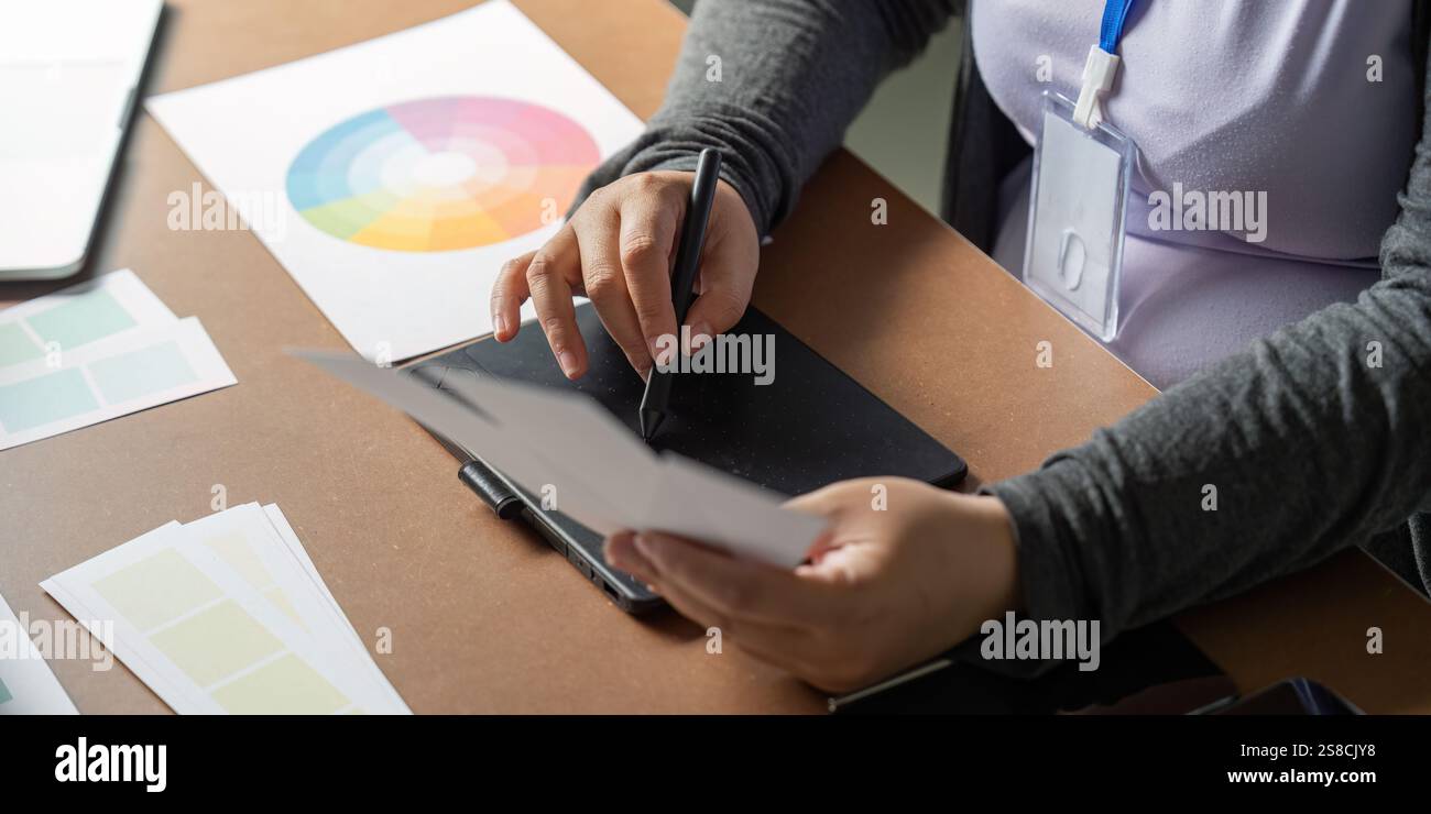 Graphic designer sketching ideas on a tablet while examining color ...