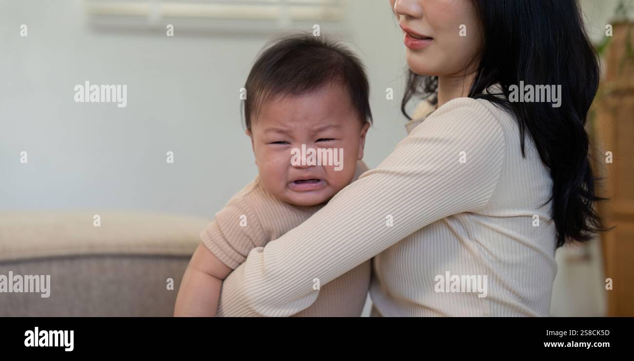 Mother soothing crying baby, experiencing emotions in a calm home setting Stock Photo - Alamy