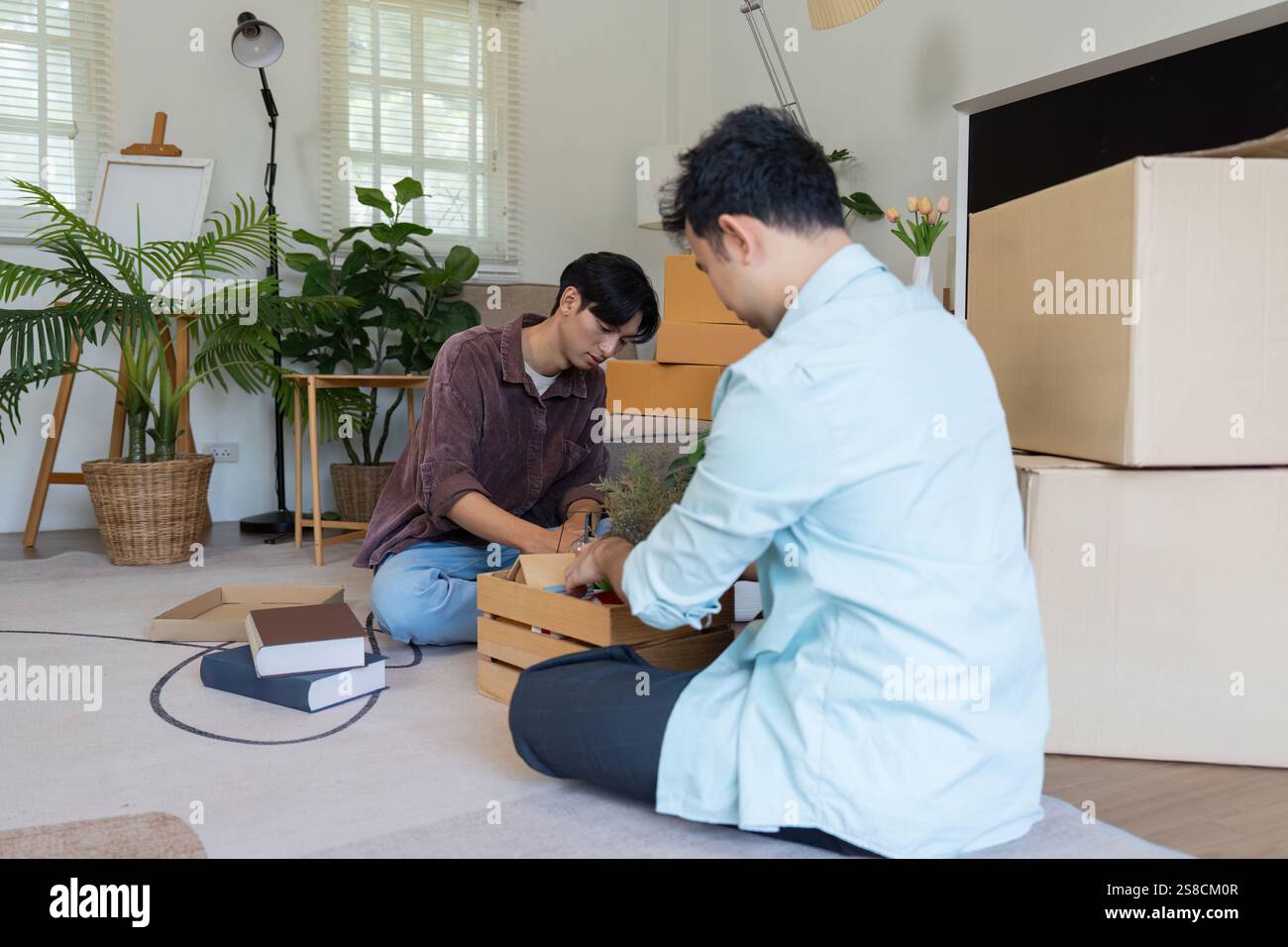 Gay couple unpacking boxes together in their new living room ...