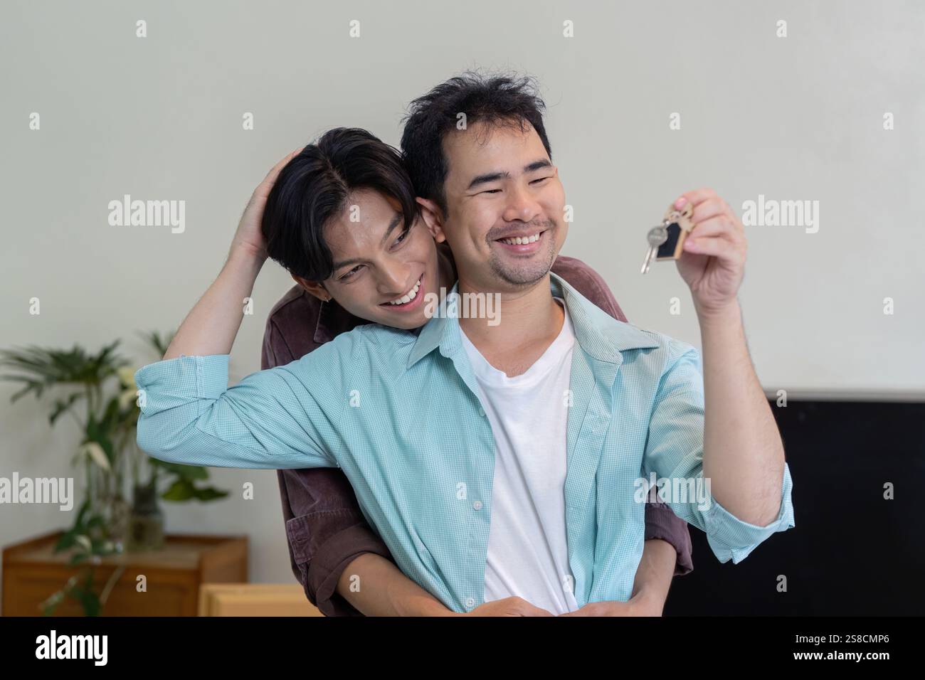 Happy gay couple holding house keys, celebrating their new beginning ...