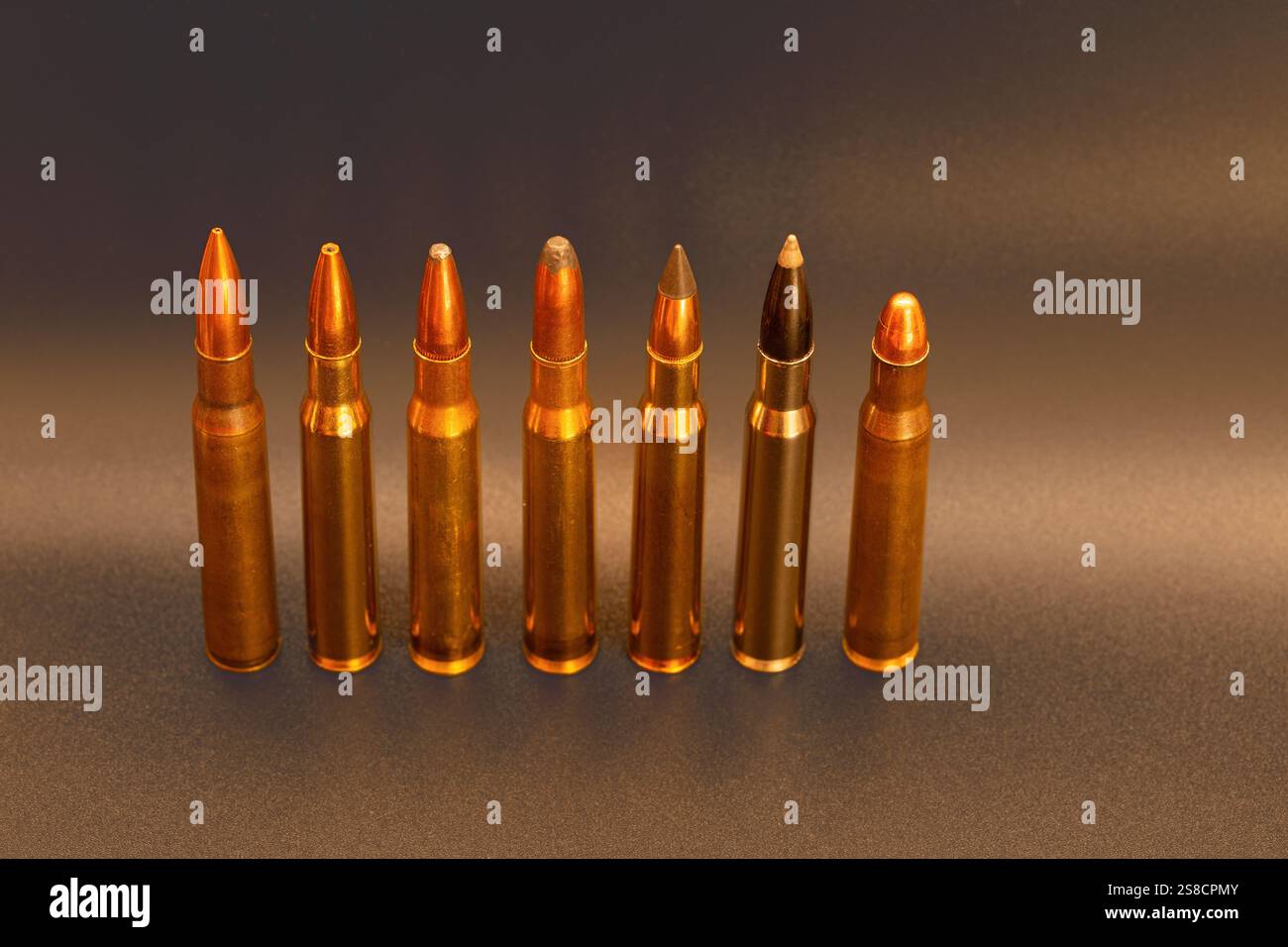 Seven rifle cartridges arranged upright on a dark background ...