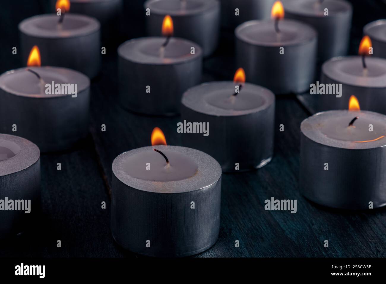Tea light candles on a dark background, many lights in the dark ...