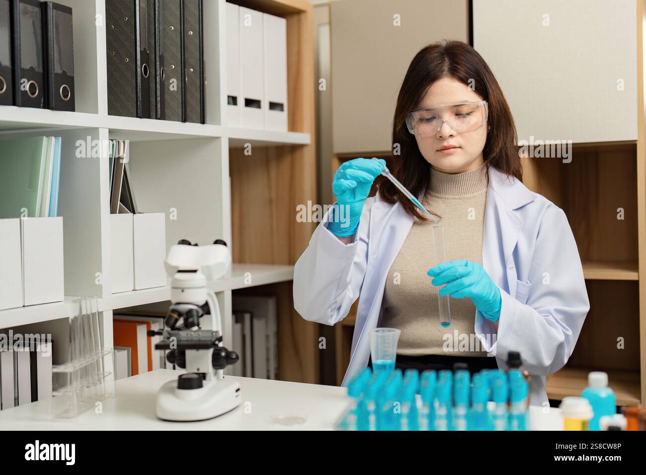 Female scientist conducting liquid analysis using a pipette and test ...