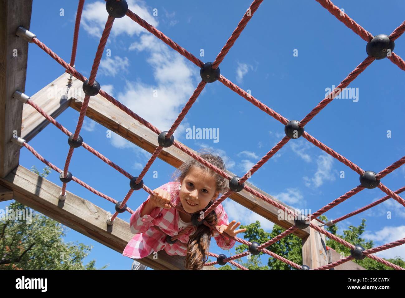 A girl rolls down a steep children's slide on the Playground. Girl ...