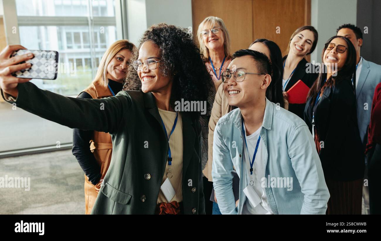A diverse team of successful coworkers happily taking a selfie together at work during a daytime ...