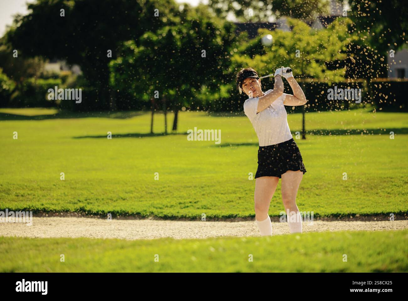 Female pro golfer making an impressive action shot from the sand bunker ...