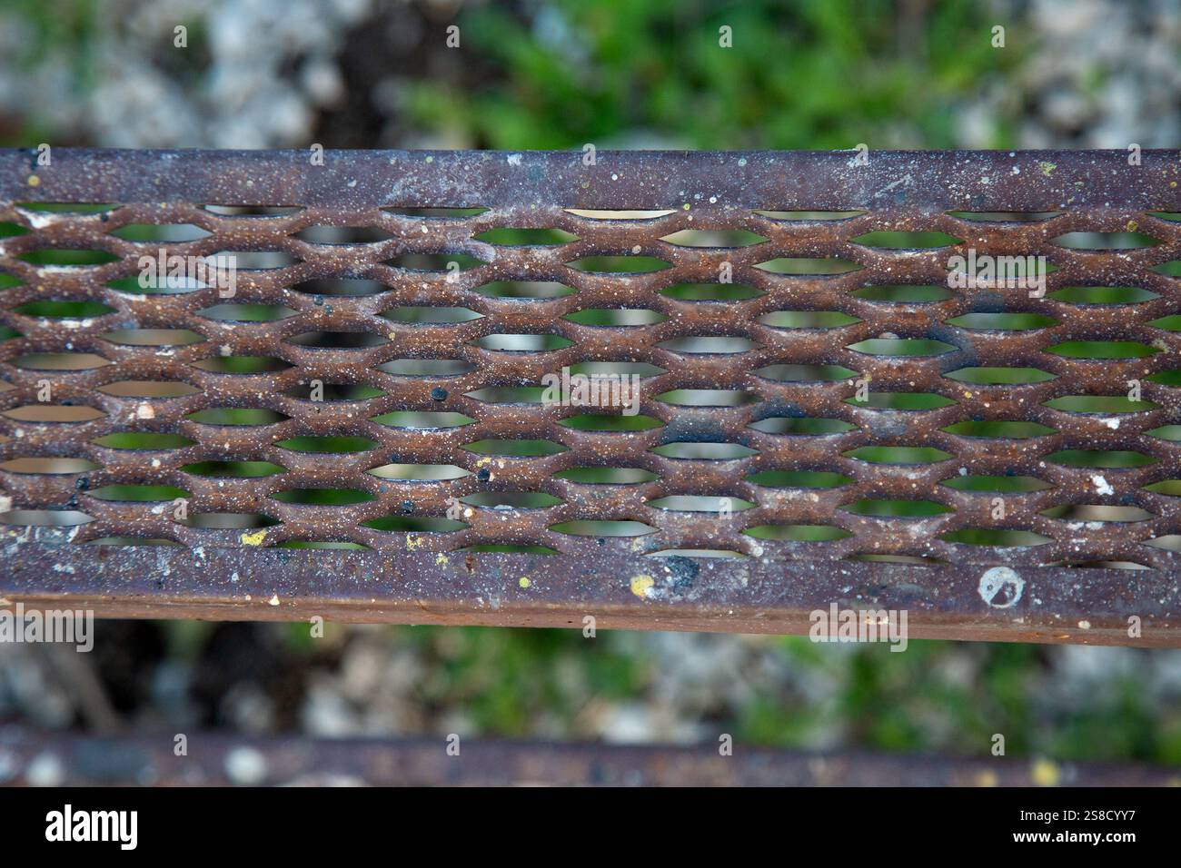 A detailed close up view of a rusty metal grate featuring holes in it ...