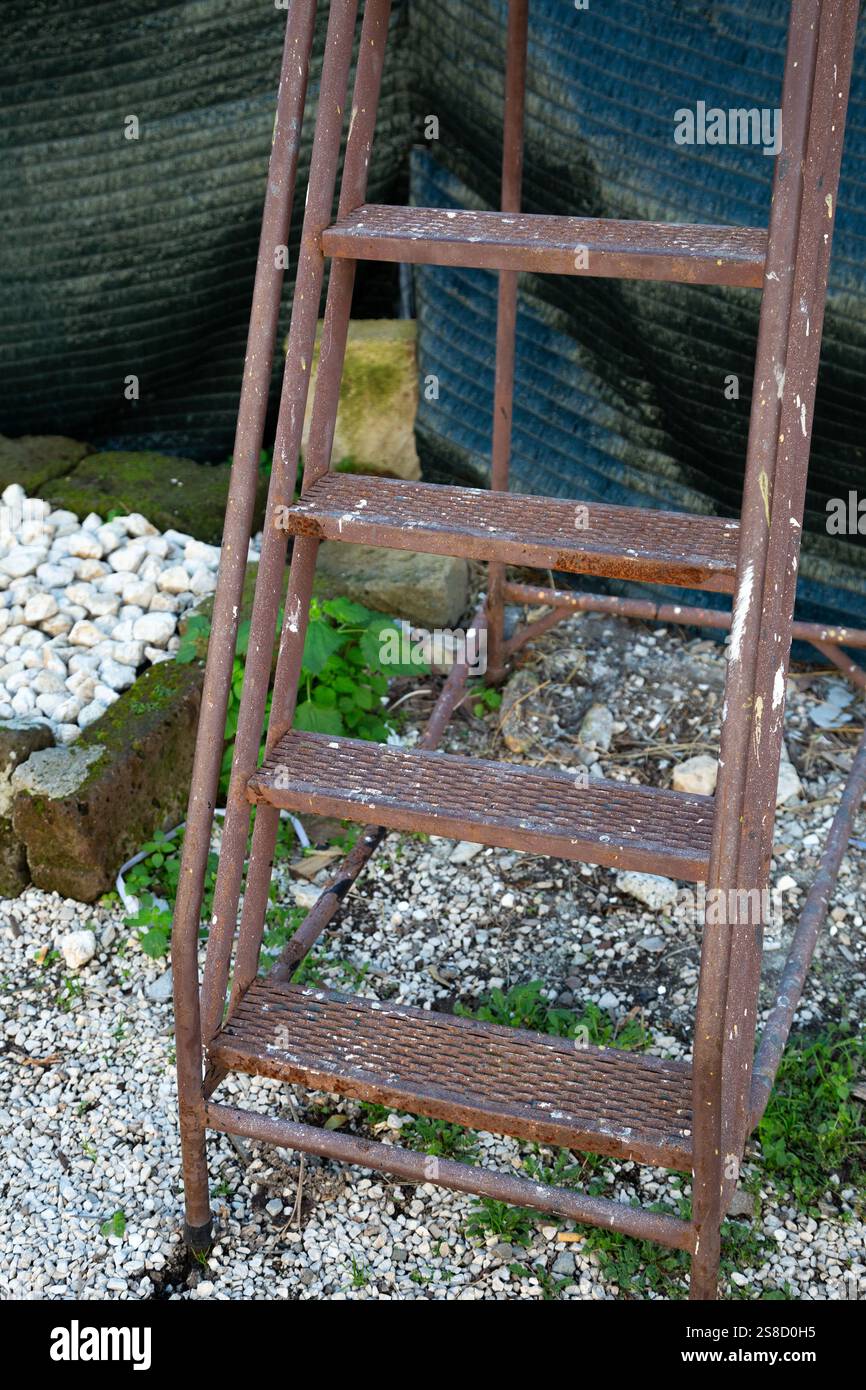 A rusty old metal ladder is sitting motionless in the dirt Stock Photo ...