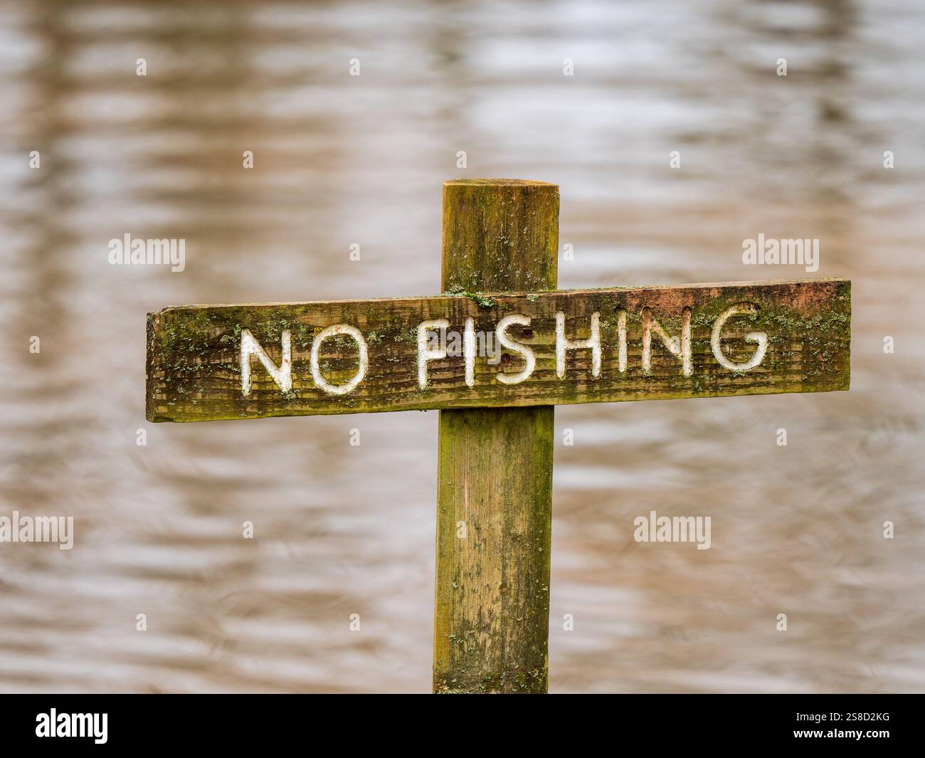 Wooden post and rail no fishing sign in the river plain water ...