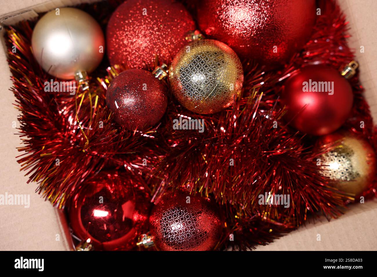 Shiny tinsels and baubles in cardboard box, top view Stock Photo - Alamy