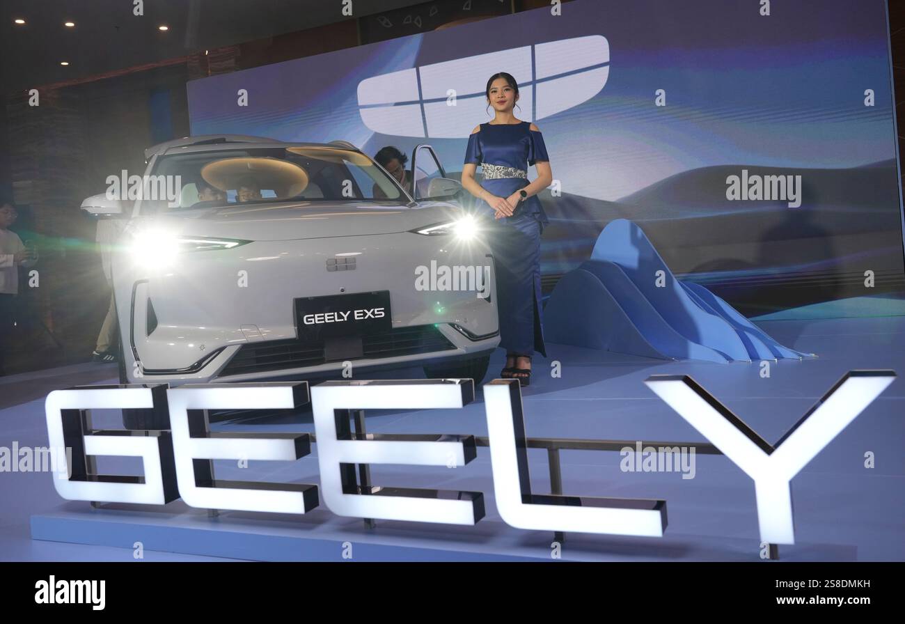 A model stands next to a Geely EX5 electric car during Geely auto brand ...