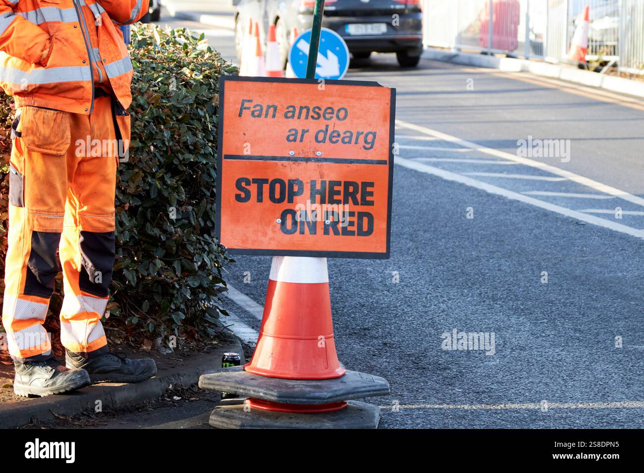 stop here on red in irish and english at roadworks directed by worker ...
