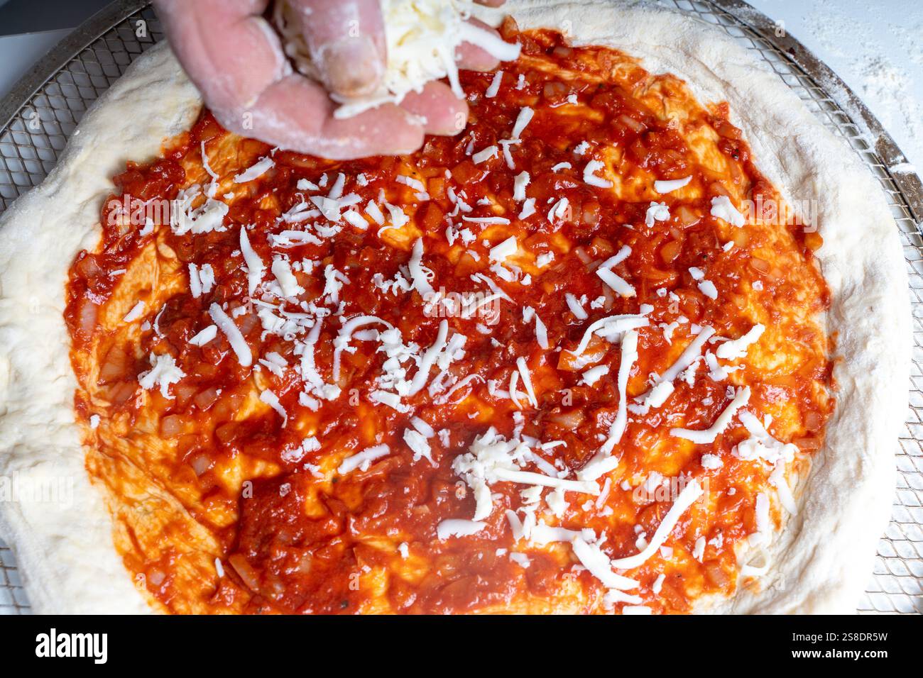 Men's hands sprinkle cheese on pizza. The process of making pizza ...