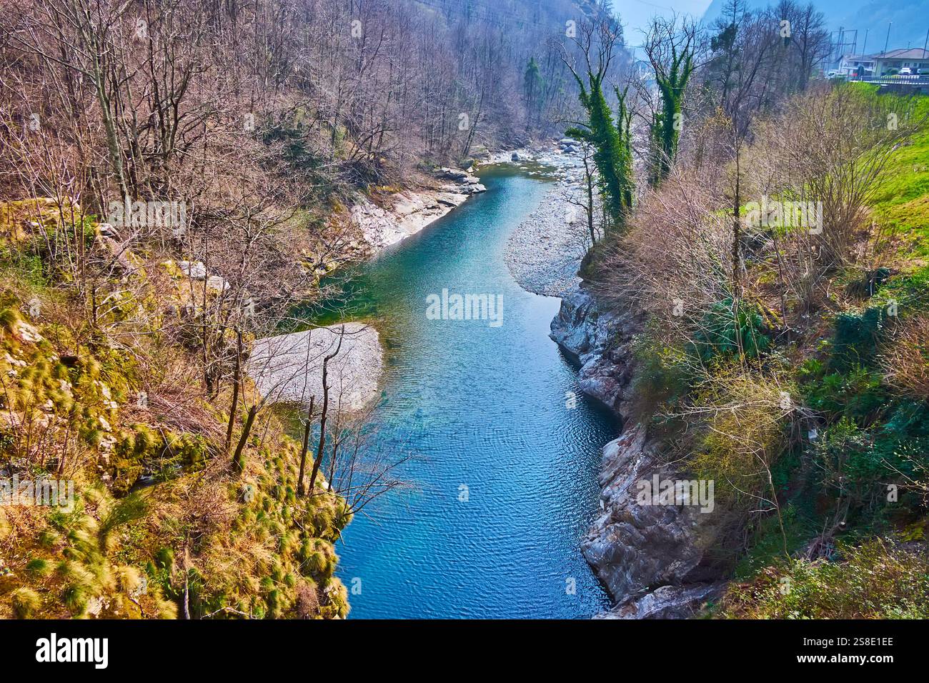 The narrow curved shallow River Maggia, surrounded with mountain slopes ...