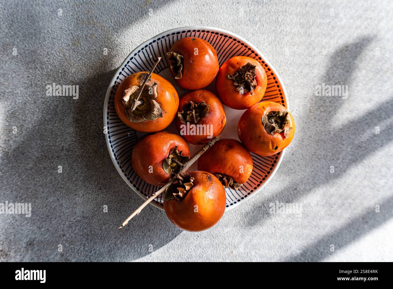 A close-up top view of freshly picked ripe persimmons neatly arranged ...