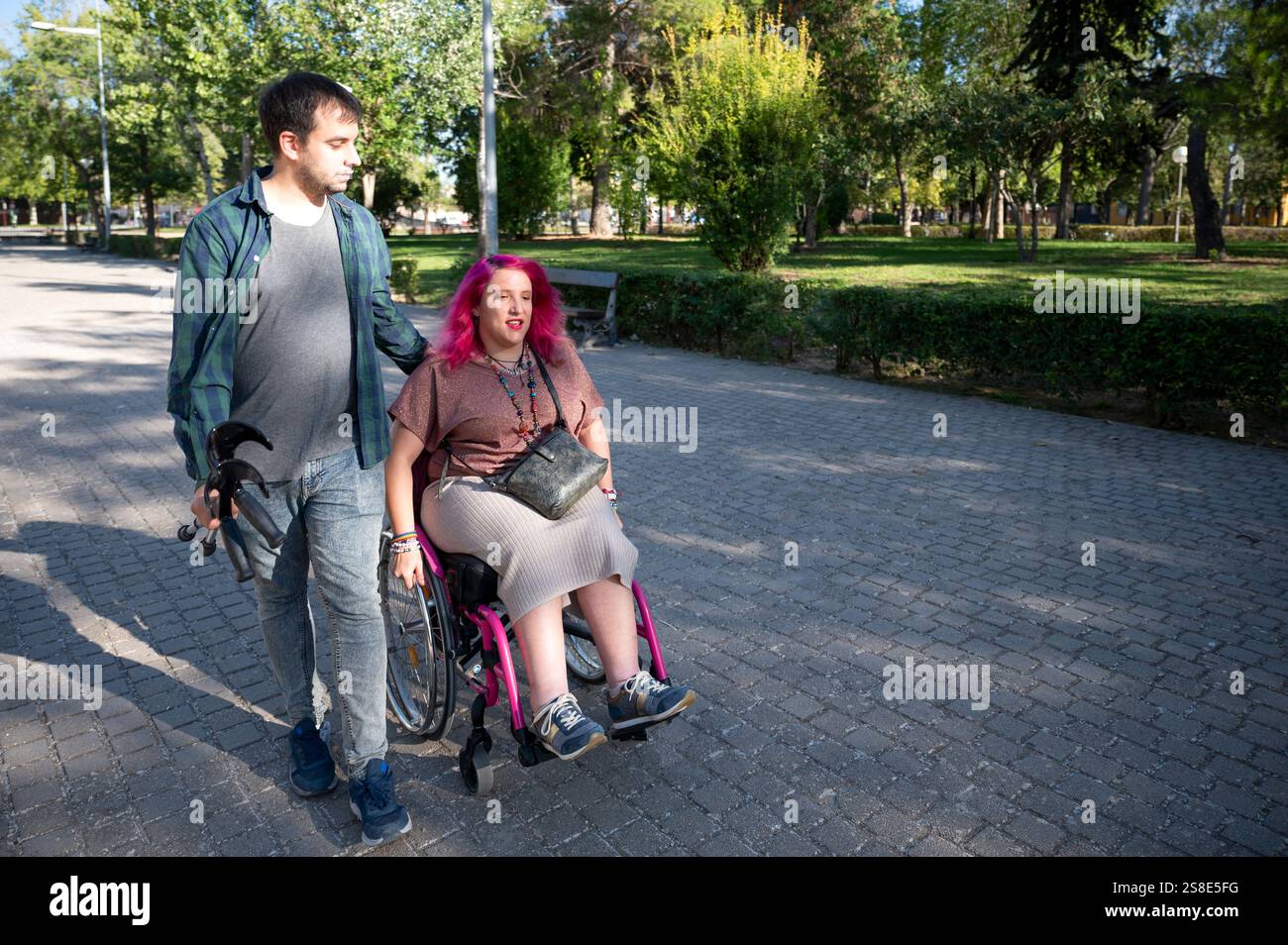 A college couple enjoying a walk on campus The woman is in a wheelchair ...