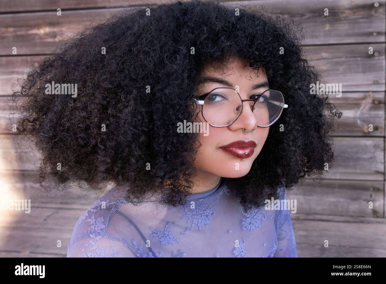 A confident young Hispanic Gen Z woman with curly hair and glasses ...