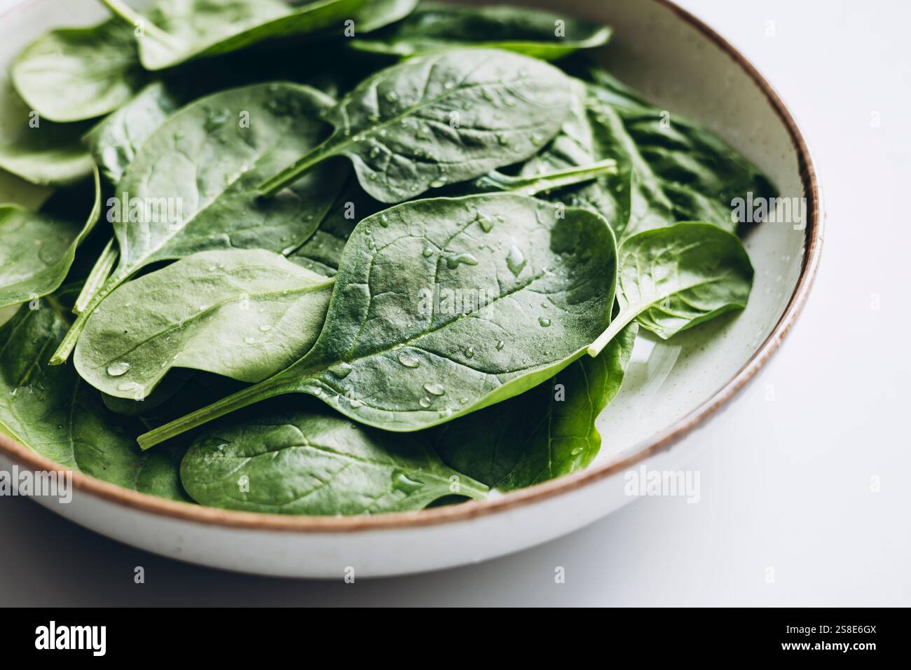 A close-up of fresh green spinach leaves in a bowl, showcasing their ...