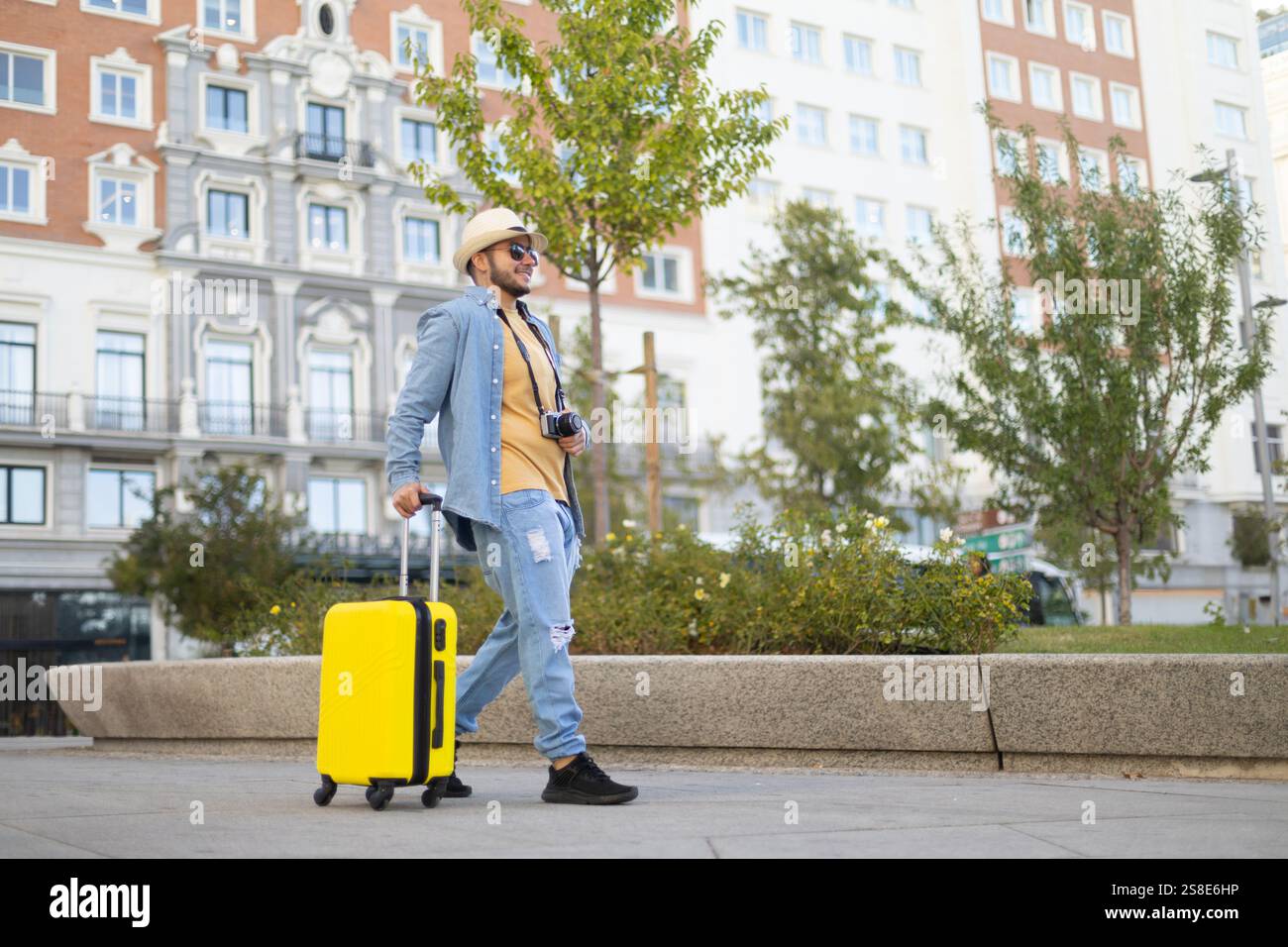 A latino transgender man in urban attire walks confidently with a ...