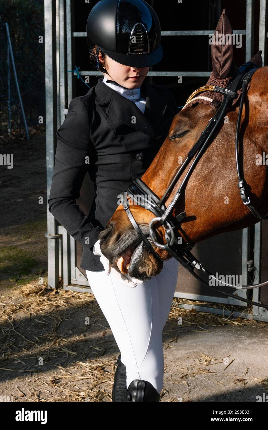 A teenage girl in classical dressage attire tenderly interacts with her ...