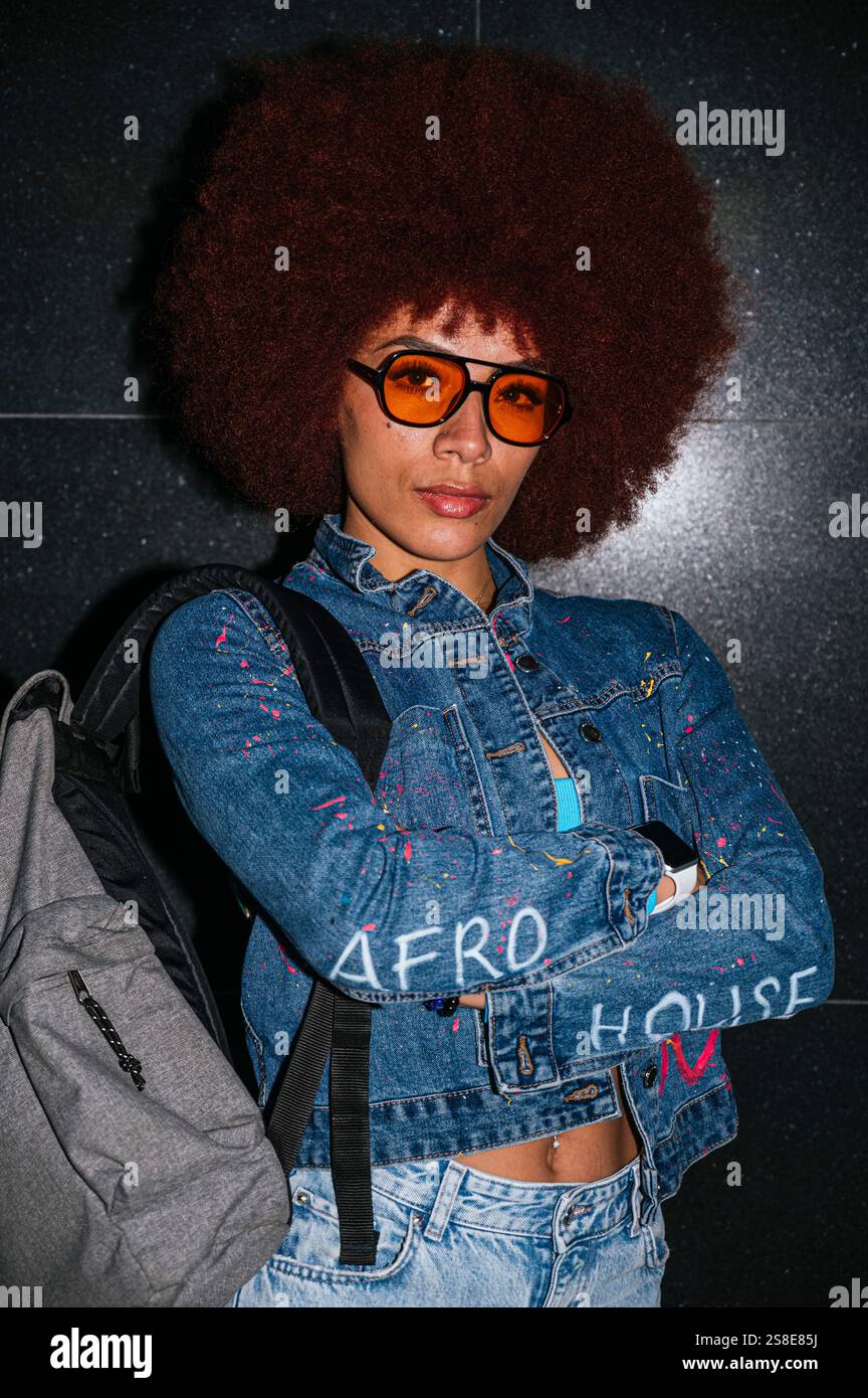 African descent woman with a voluminous afro hairstyle wearing orange ...