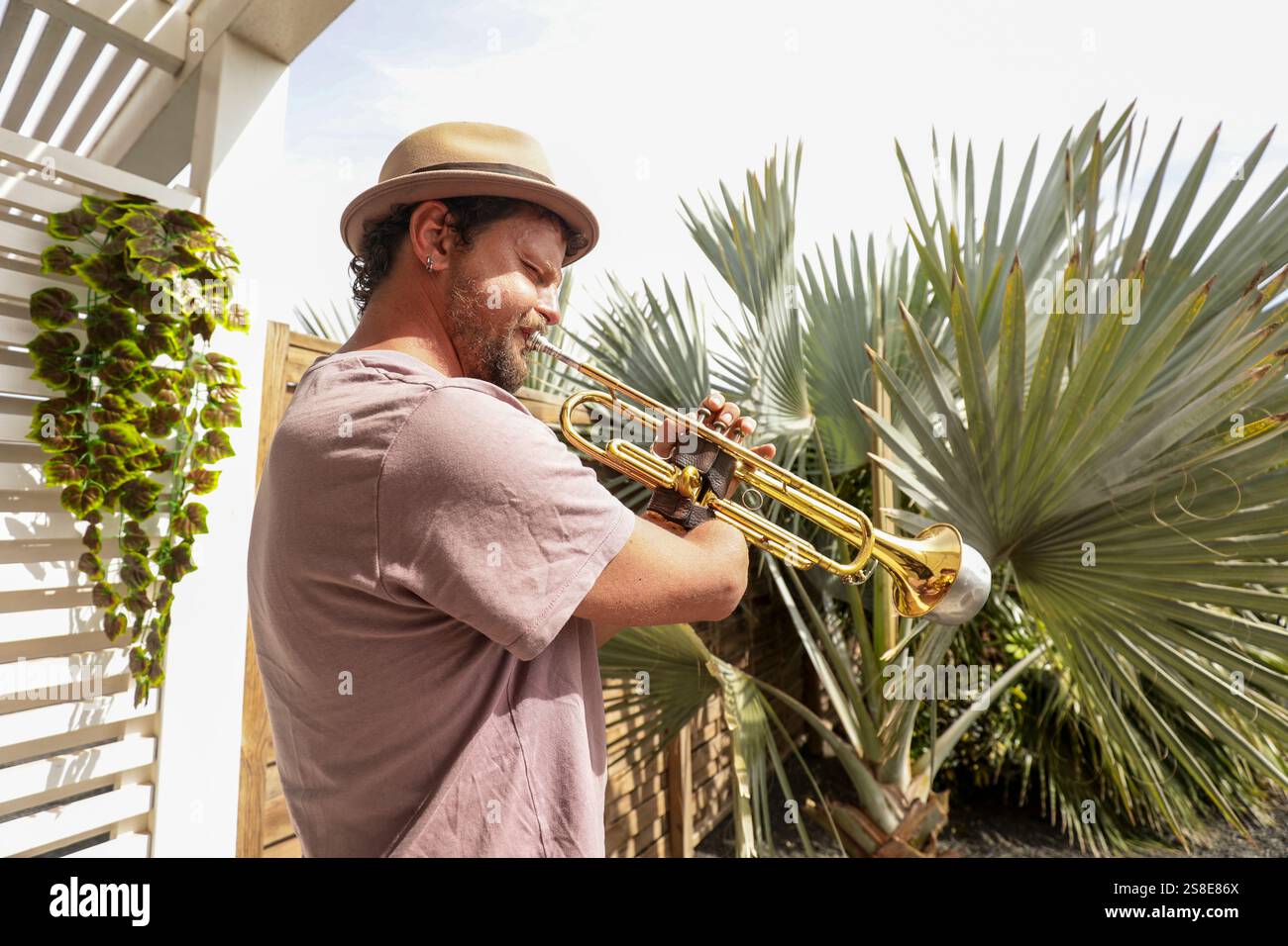 A talented one-armed man wearing a hat plays a trumpet outdoors ...