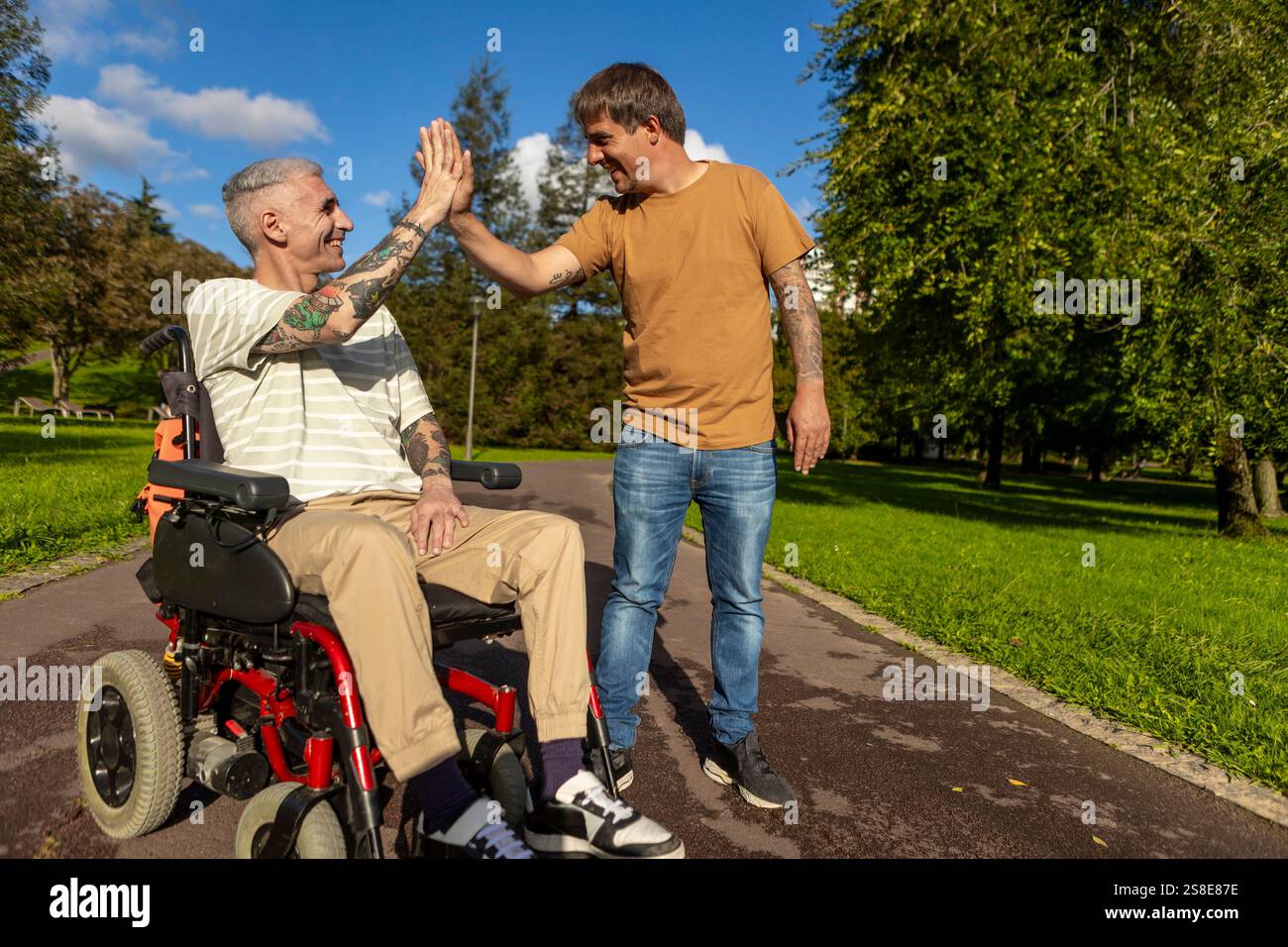 A joyful moment in the park, as two friends share a high-five One is ...