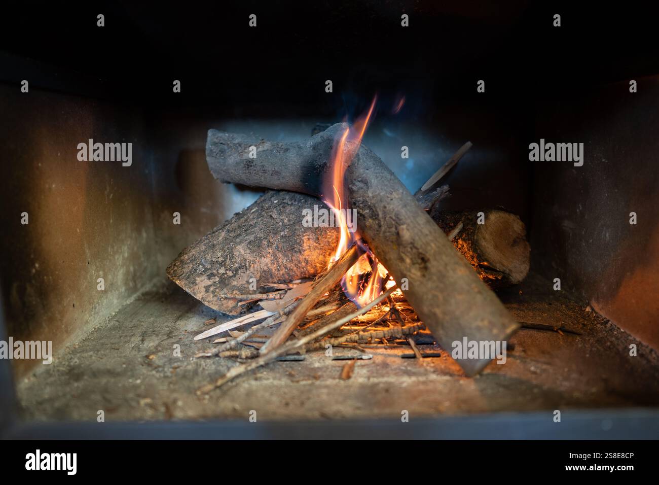 Close-up view of burning wood logs and kindling inside a wood burning ...