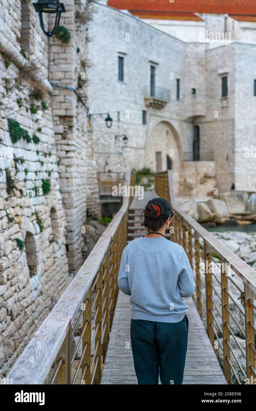 A person walks along a wooden bridge leading to the historic stone ...