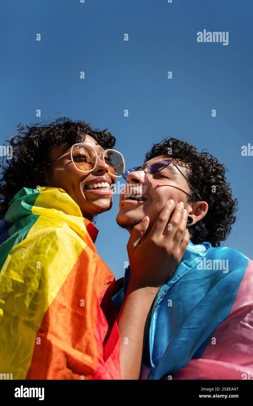 A joyful LGBTQ+ couple sharing a loving moment under a clear sky ...