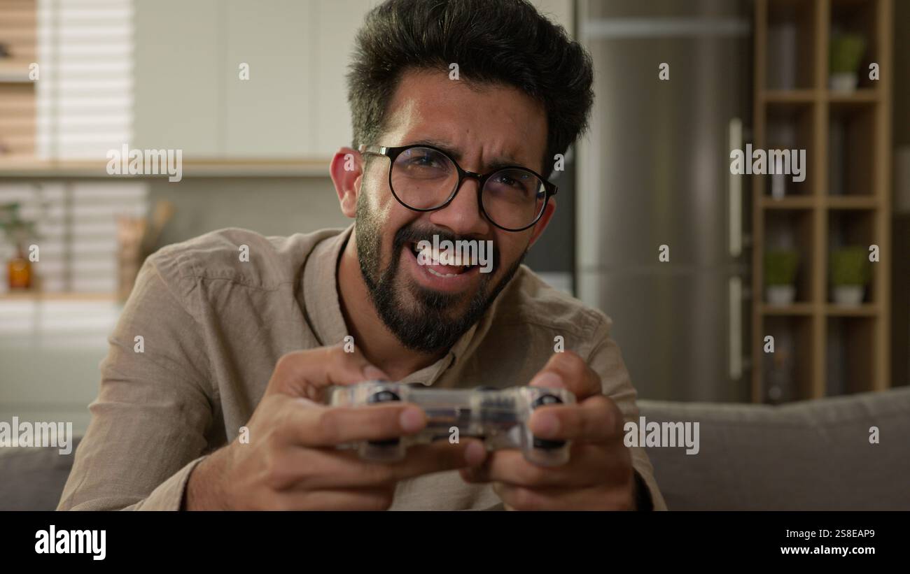 Addicted male gamer Arabian Indian man guy on couch play video game ...