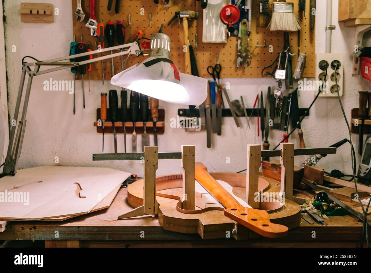 A detailed view of a luthier's workshop where a bass guitar is being ...