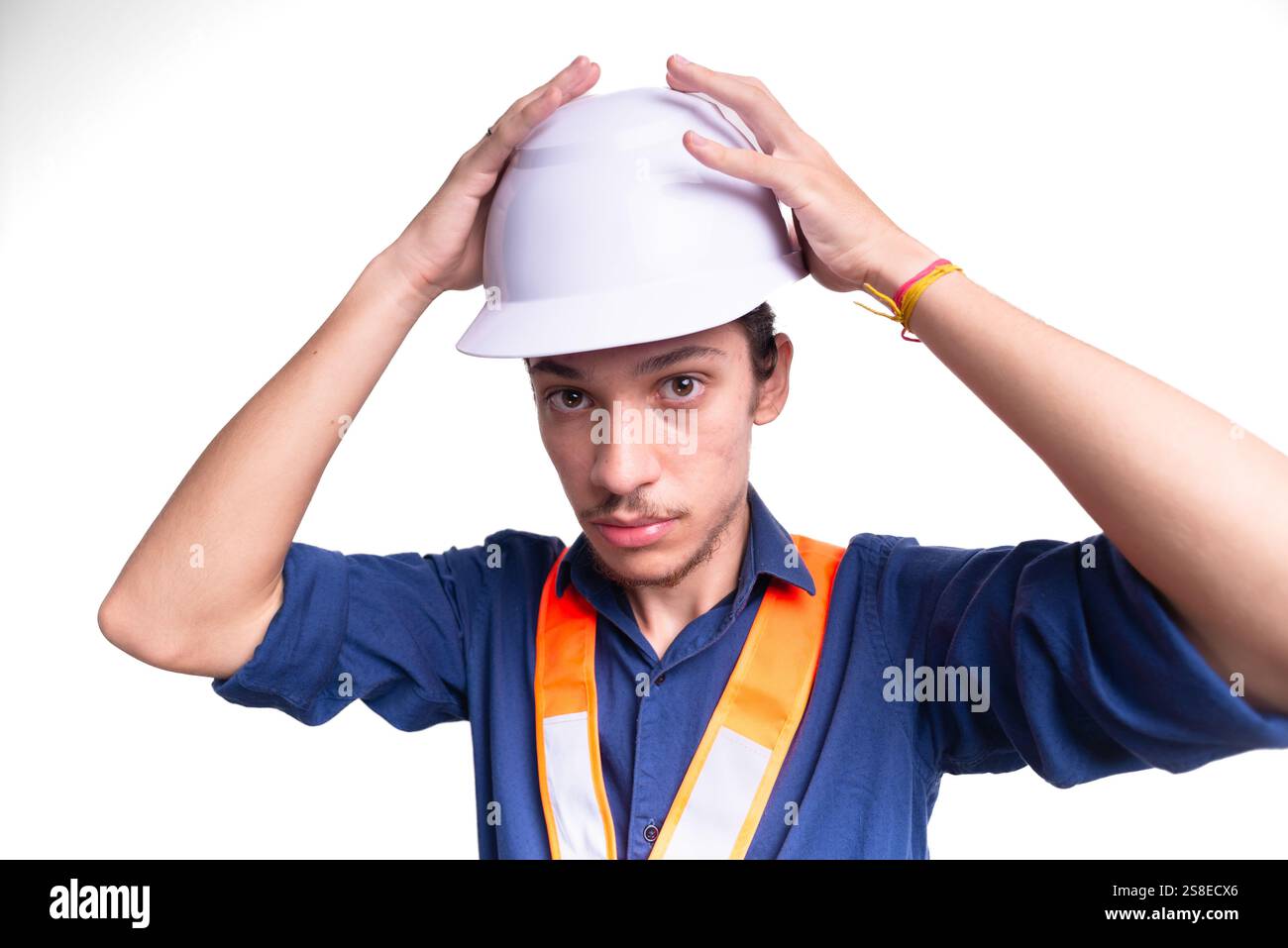 Young engineer adjusting white helmet on head, wearing luminous vest ...